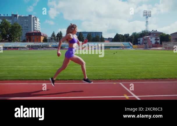 Young woman sprinting on track at the stadium. Female athlete running ...