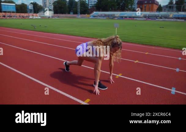 Young woman sprinting on track at the stadium. Female athlete running on track. Beautiful woman ...