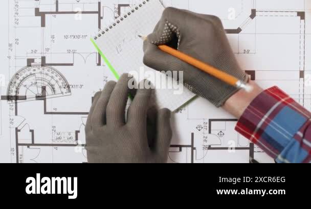 Engineer writes marks in notepad measuring floor plan with protractor ...