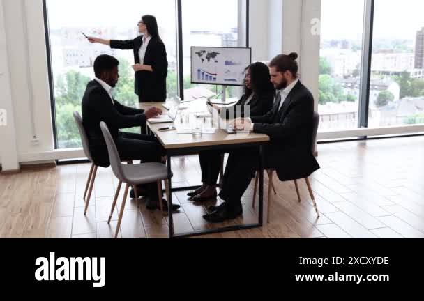 Business team in formal attire engaging in presentation with charts and ...