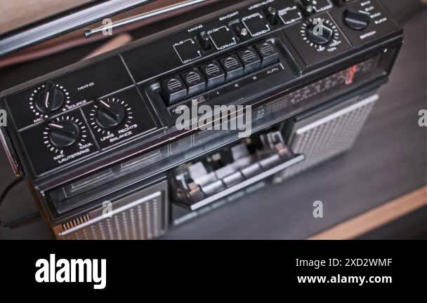 A hand interacts with the buttons and dials of a vintage boombox ...