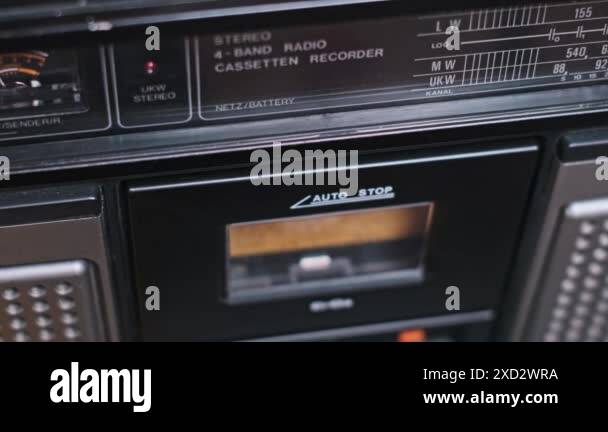 A hand loads a vintage cassette tape into a boombox, ready to enjoy the ...