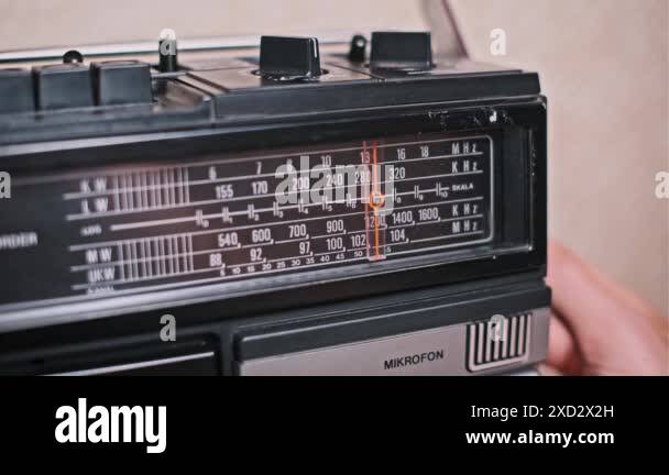Close-up of a vintage boombox radio dial as a hand adjusts the tuning ...