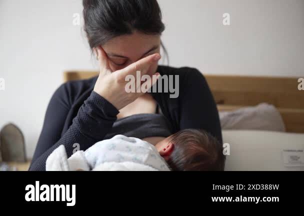 Mother yawning while breastfeeding her newborn baby. visibly tired ...