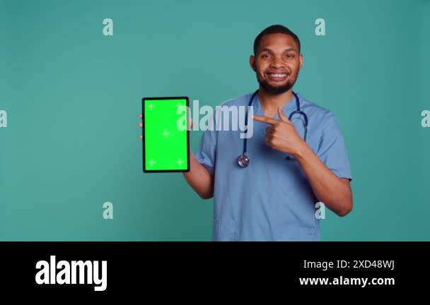 Portrait of male nurse showing medical instructions video on green ...
