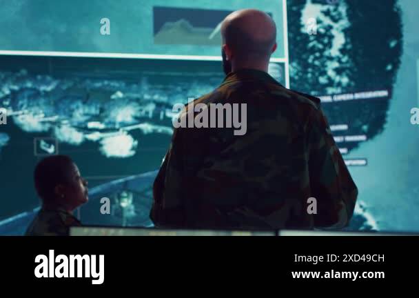 Army officer examining real time satellite data on big screen in ...