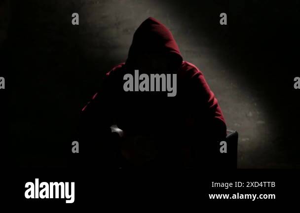 Anonymous man in a hood interview video footage. Mysterious man sitting ...