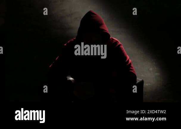 Anonymous man in a hood interview video footage. Mysterious man sitting ...