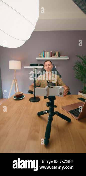 A vlogger recording content in a home studio, featuring a microphone, camera, and laptop for ...