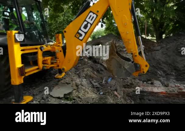 Kharkiv, Ukraine - June, 08, 2024: An excavator slowly lowers a bucket ...