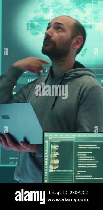 Vertical Video Governmental hacker examines info on a big screen in agency office, using ...