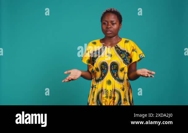 Uncertain woman acting confused and raising shoulders in studio, being ...