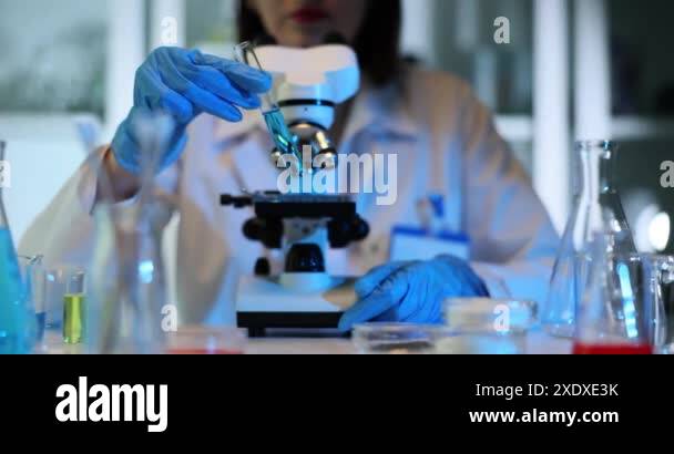 Woman medical worker shakes test tube with blue reagent in lab. Female ...