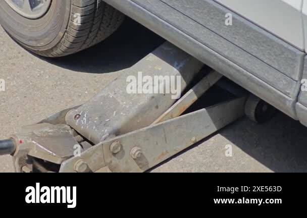 Mechanic lifts the car using an automotive hydraulic floor jack Stock ...