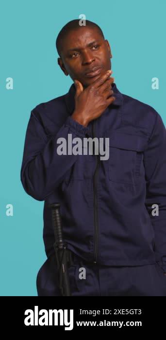 Vertical video Security guard doing thinking hand gesture, being tasked ...