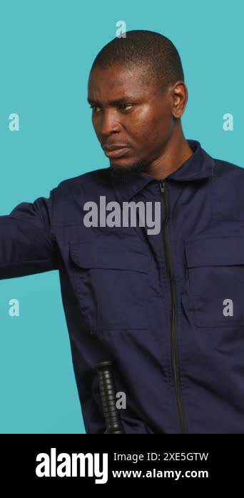 Vertical video Security guard pointing finger at people to prevent them ...