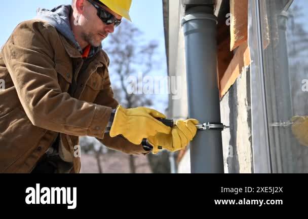 Construction Worker is Installing Gutter Downspout on a House Exterior Stock Video Footage - Alamy