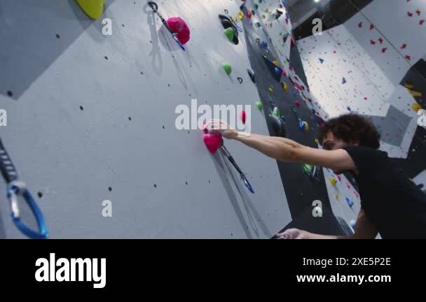 athletic man scaling an indoor rock climbing wall in a modern gym ...