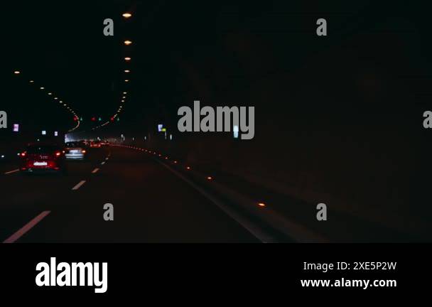A dynamic scene of cars driving through a tunnel, with overhead lights ...