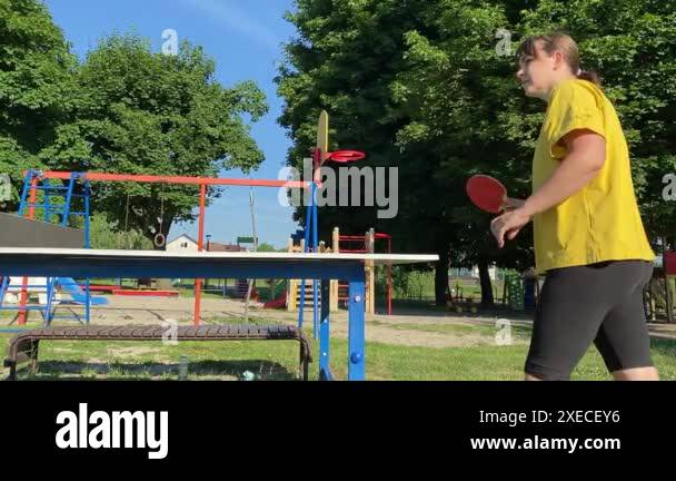 A young woman in athletic wear energetically plays ping-pong on a ...