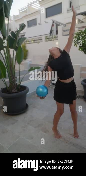 Young girl practicing rhythmic gymnastics with a blue ball in an ...