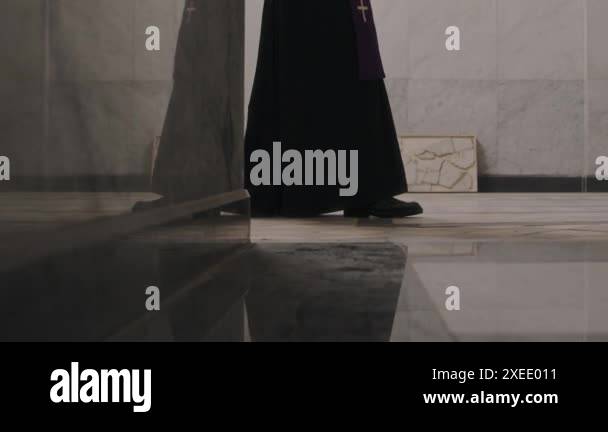 Low section shot of legs of unrecognizable priest wearing black cassock ...