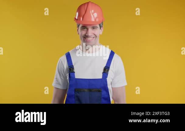 Friendly foreman in overall and helmet showing yes signal, nods head ...