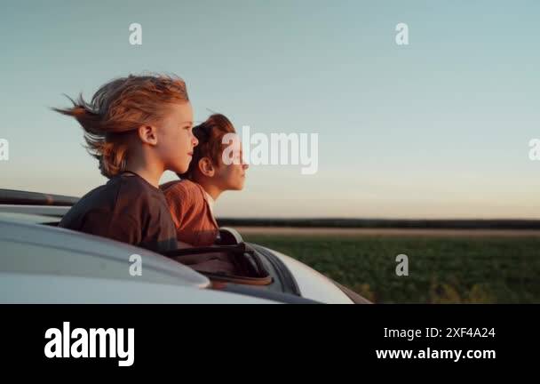 Adorable happy little kids stands in open car sunroof during road trip ...