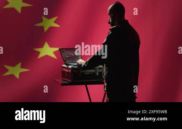 Chinese army military dispatcher looking at surveillance transmission on laptop, relaying ...