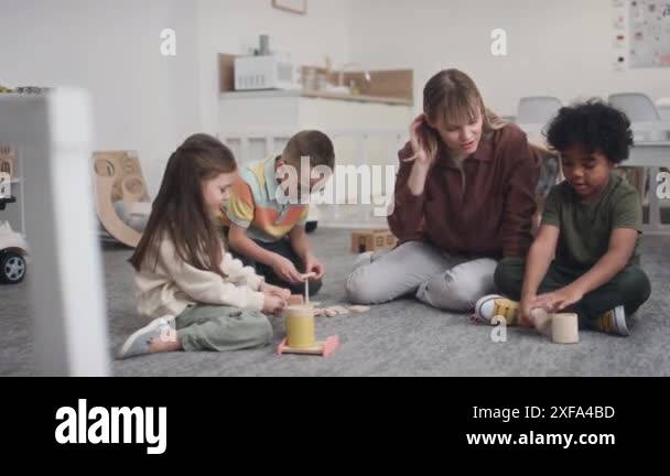 Full shot of group of diverse preschool children sitting on floor in ...