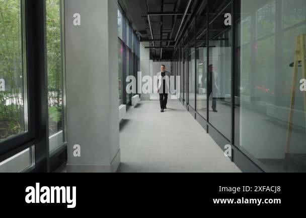 Man in business suit walks down corridor of modern office building ...