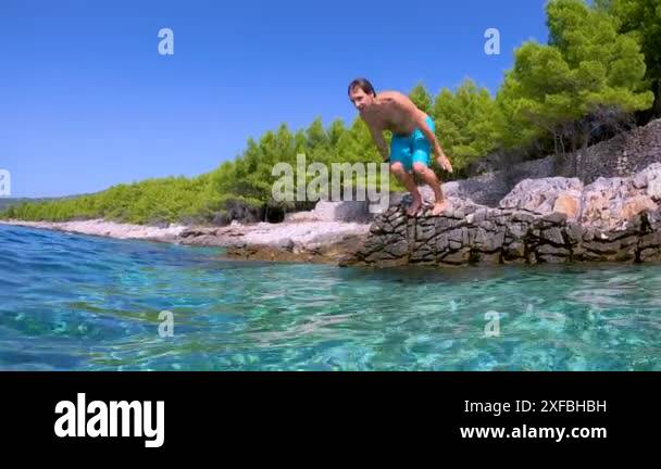 SLOW MOTION: Carefree vacationer jumps head first into crystal clear ...