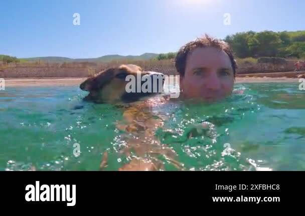 SELFIE: Happy young man and his adorable dog swim side by side in ...