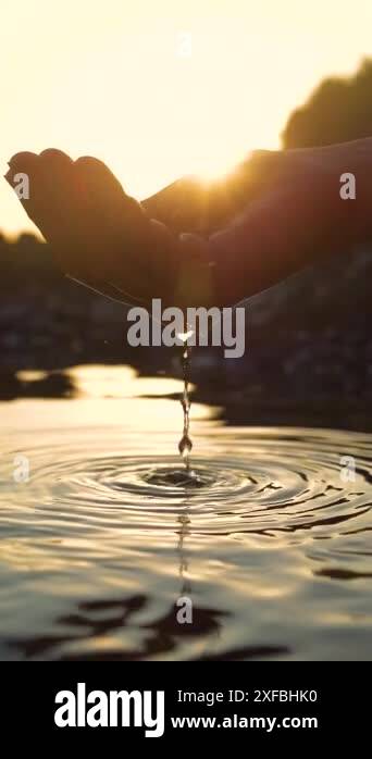 LENS FLARE, VERTICAL: Water droplets fall from the palm of a hand ...