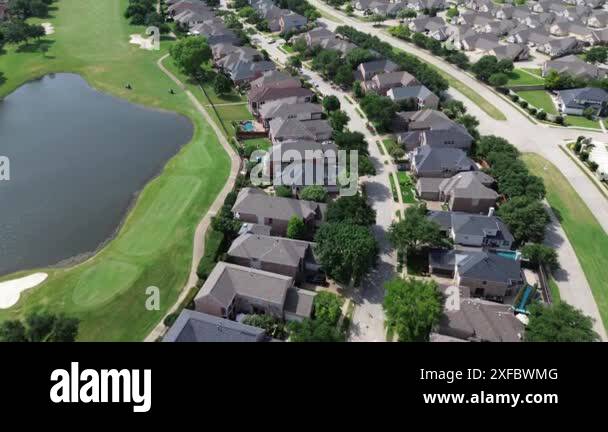 Club cars moving in residential golf course along upscale large mansion ...