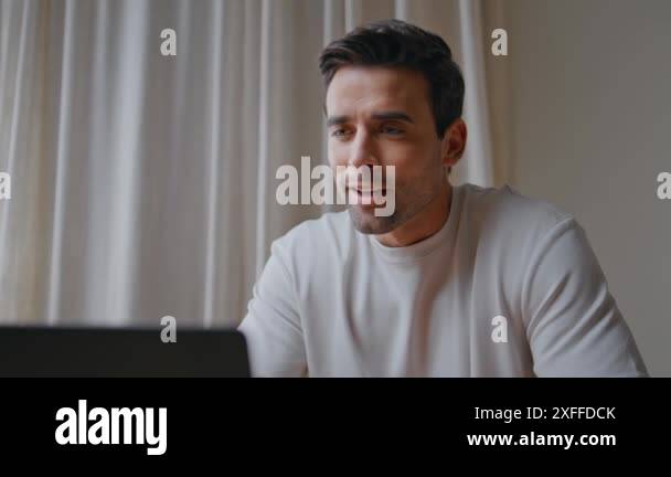 Guy freelancer talking at virtual meeting looking laptop web camera on remote workplace closeup ...