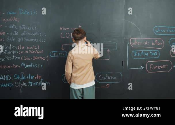Back view of smart boy writing engineering prompt on blackboard. Attractive happy student ...