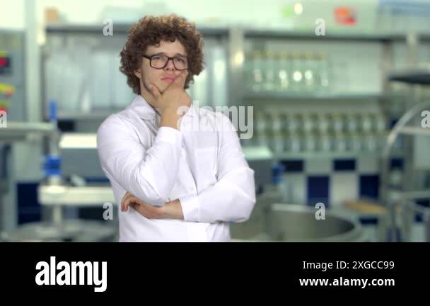Young handsome scientist with curly hair thinking touching his chin ...