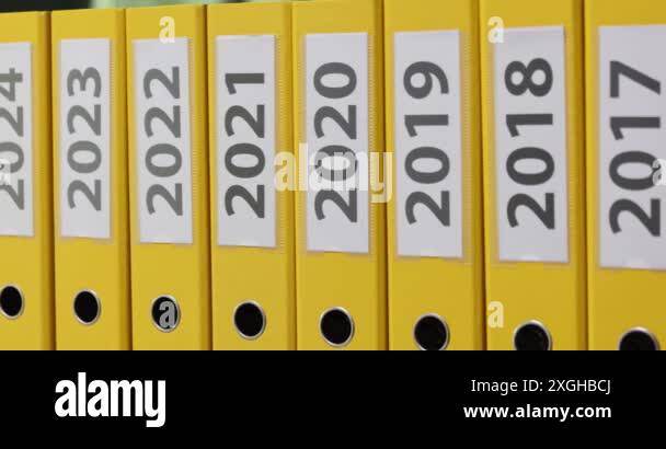 Folders stand neatly on shelf in chronological order. Yellow ring ...