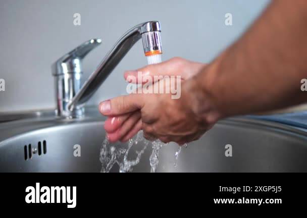 Close-up of faucet and hands, washing hands under trickle water ...