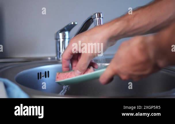 Hands and faucet close-up, man washing plate under running water ...