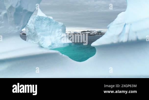 Cracked hole in melting iceberg in Antarctica ocean close up. Drone fly ...