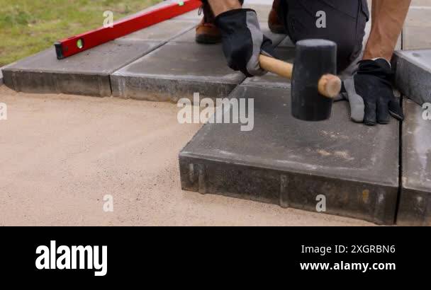 man laying concrete paving slabs with rubber hammer. terrace pavement ...
