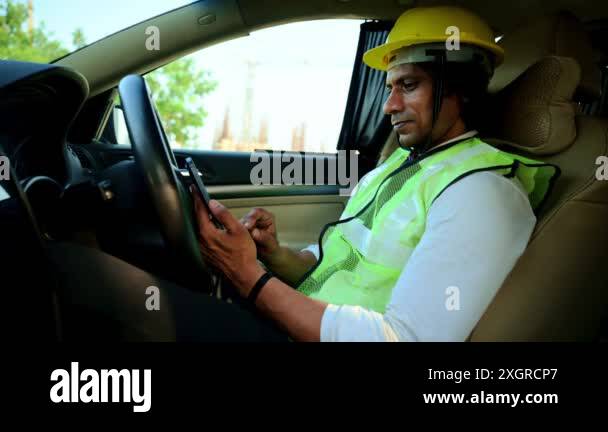 Civil engineer wearing safety helmet and vest scrolling on a mobile ...