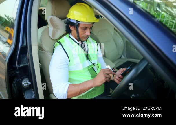 Civil engineer wearing safety helmet and vest scrolling on a mobile ...