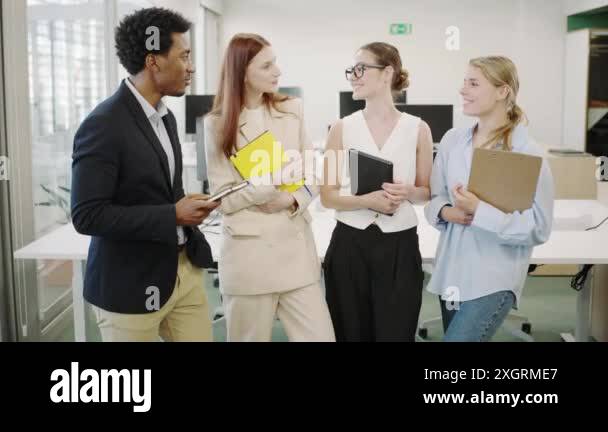In a modern workspace, four diverse office employees engage in a collaborative business meeting ...