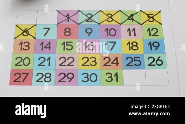 A person marking days on a colorful calendar with a black marker ...