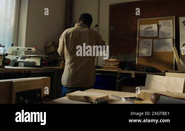Back view of professional male carpenter standing in woodworking ...