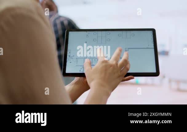 Real Estate Agent And Client Evaluating Blueprints And Discussing The