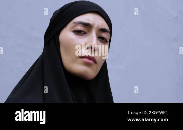 Close-up serious and sad face Muslim woman in hijab. Muslim expresses deep emotions with gaze ...